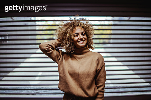 Smiling mixed race rap girl standing in front of garage door and ...