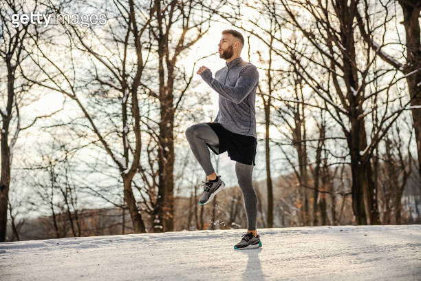 Fit sportsman running in nature at snowy winter day. Cold weather ...
