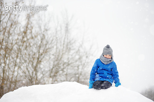 Little boy enjoy riding on ice slide on snowy day. Baby having fun ...