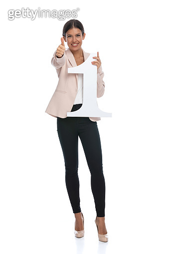 attractive young girl making thumbs up gesture and holding number one ...