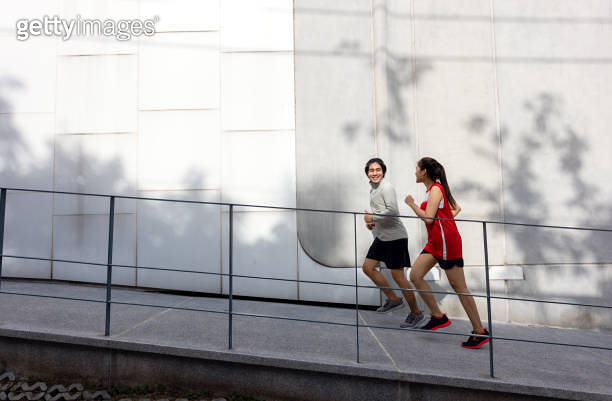 Running pair exercising outside in the city in an urban living active ...