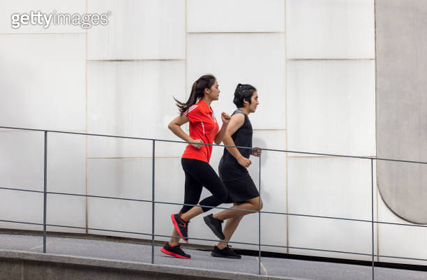 Running pair exercising outside in the city in an urban living active ...