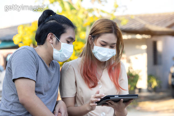 Young asia couple using smart mobile photo outdoor wearing face mask ...