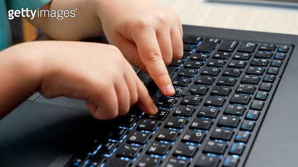 Closeup of little child fingers pressing buttons on laptop keyboard ...