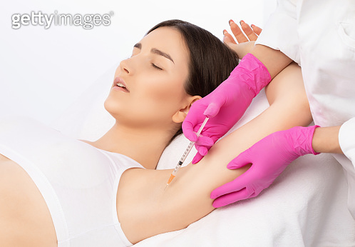 The doctor makes injections of botulinum toxin in the underarm area ...
