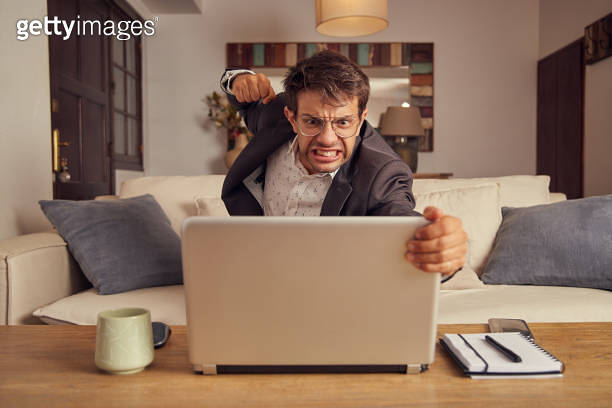 Young angry man in suit hitting the laptop computer with his fist ...