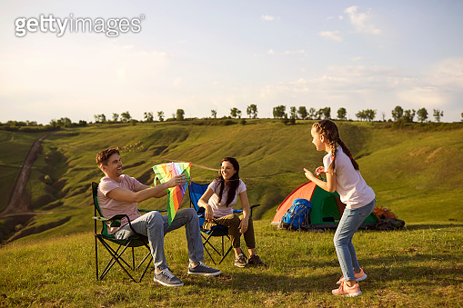 Happy family tourist on a campsite have fun playing with a kite on ...