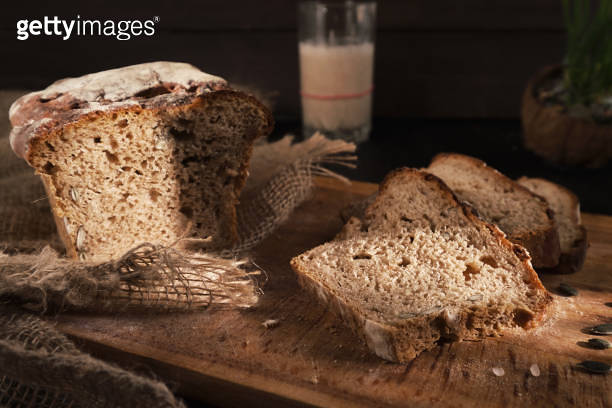 Fresh homemade leavened bread in the sun, partially sliced. Bread is ...