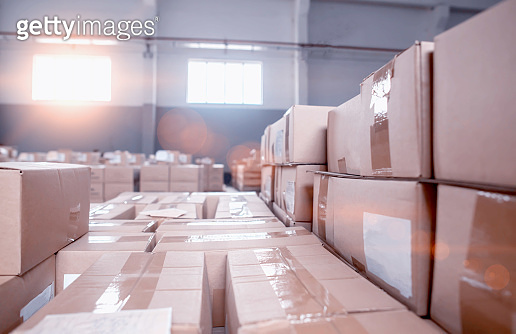 Warehouse with cardboard boxes in storage. The sunset shines through ...