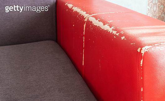 Torn and battered leather back of the sofa. Poor quality leather ...