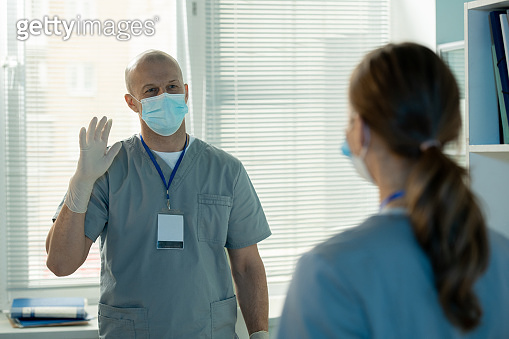 Mature male medical laboratory worker waving hand to his young female ...