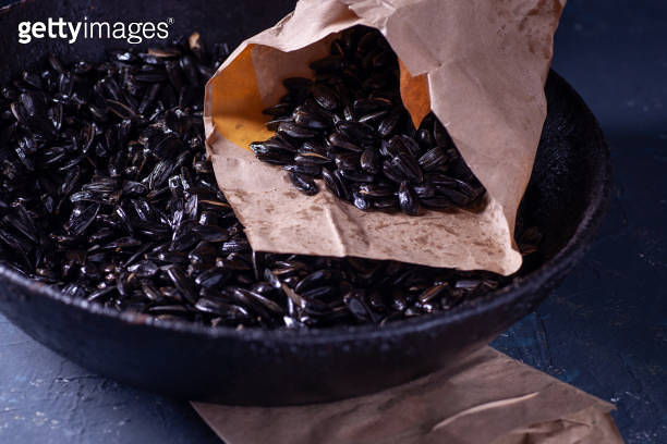 sunflower seeds in a paper craft bag and in a black charred cast iron ...
