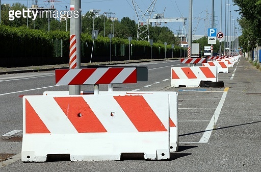 Red and white painted concrete block road barriers at the side of the ...