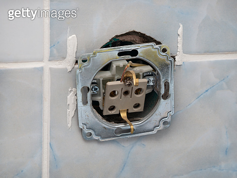 Disassembled, torn out electrical socket with bare wires in the ...