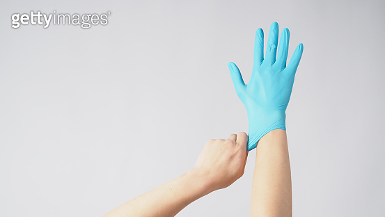 Left hand is pulling right hand with blue latex gloves on white ...