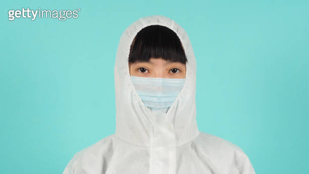 Asian Woman wear face mask and PPE suit on mint green or Tiffany Blue background. 이미지 ...