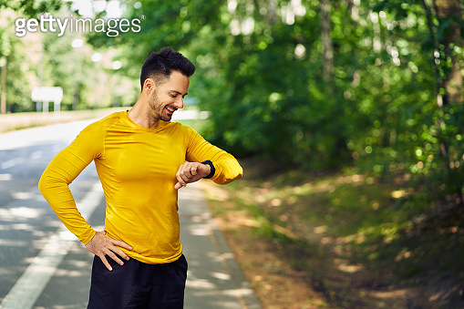 Male jogger checking his smartwatch while running outdoors 이미지 ...