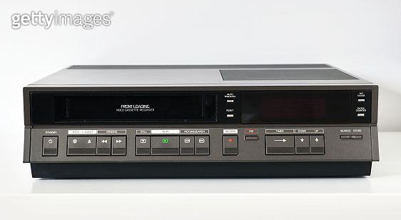 An old vintage videotape recorder from the 1980s stands on a dark table ...