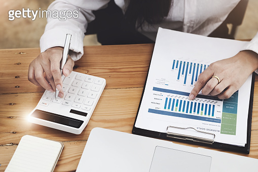 Business woman using calculator to review balance sheet annual using ...