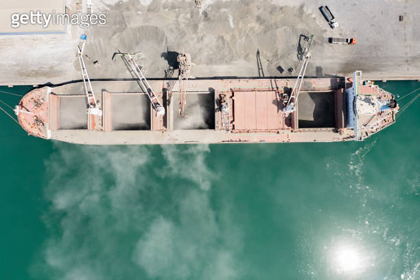 Aerial view of a large cargo ship being loaded with cement in an ...