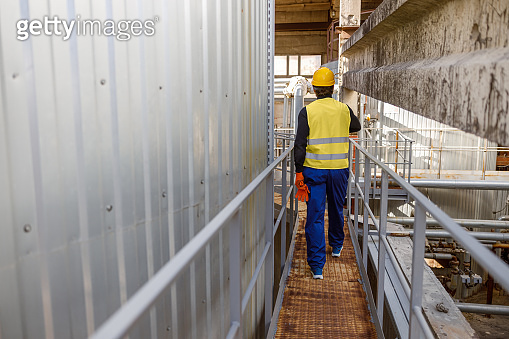 Male worker walking on metal bridge at factory 이미지 (1354697340) - 게티이미지뱅크