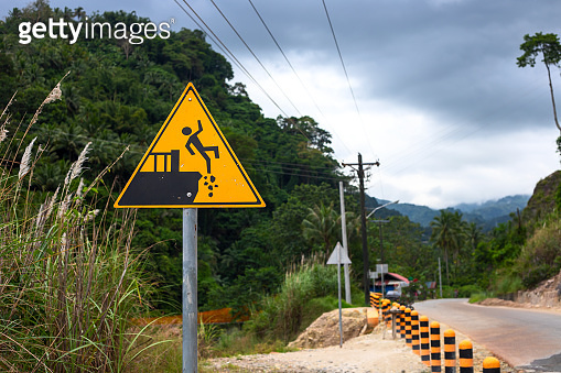 Beware cliff falling yellow sign on mountain road. Unstable cliff ...