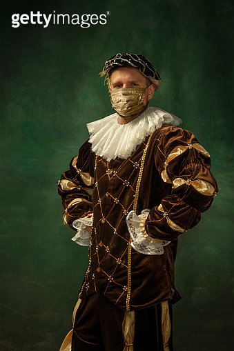Portrait of medieval young man in vintage clothing and golden face mask ...