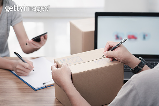 Parcel man use a pen marking address on Parcel box and women Sign ...