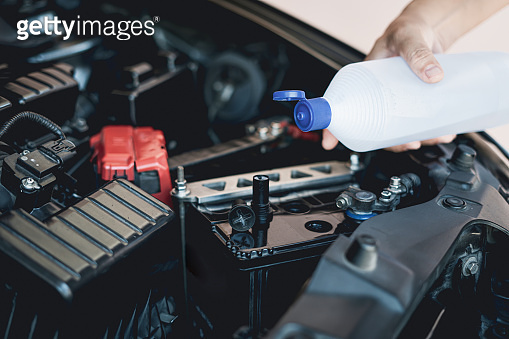 A man holding and add water to distilled the car battery maintenance ...