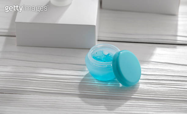 Open blue gel container on wooden white table beside window 이미지 ...