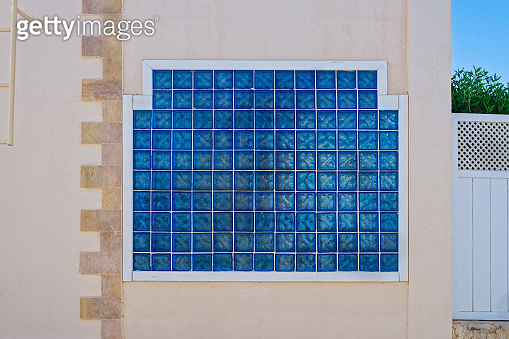 A window made of blue glass blocks is placed on a teracotta-colored ...