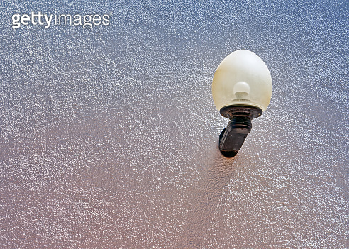 A street lamp with a black metal base is located on a white wall ...