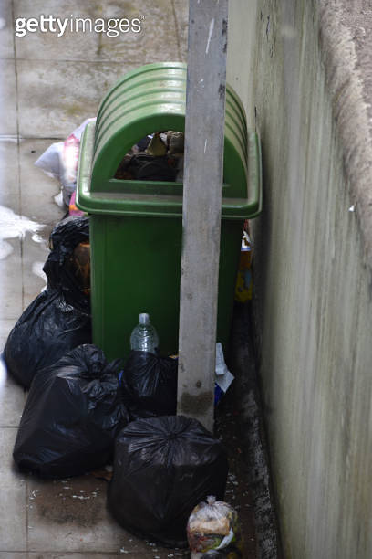Garbage bags near trash can. Stacks of litter bags overflow trash cans ...