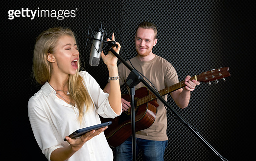 Young female singing with tablet computer in her hand. While the man ...