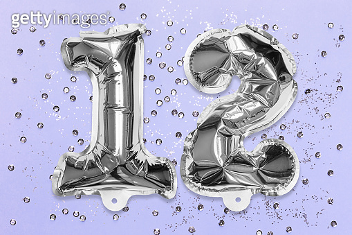 Silver foil balloon number, digit twelve on a lilac background with ...