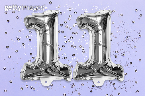 Silver foil balloon number, digit eleven on a lilac background with ...