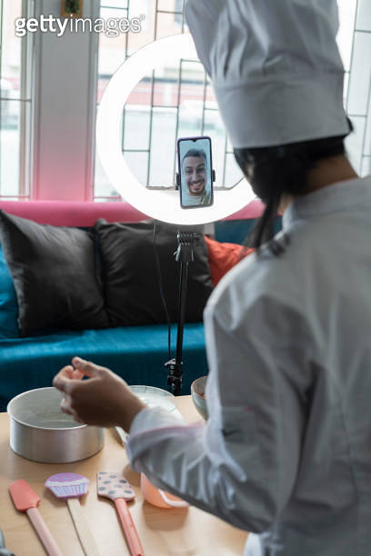 Female influencer chef speaks to her followers while doing a live show ...