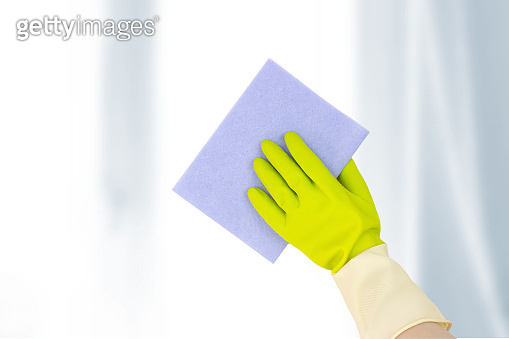 Washing windows theme. Top view of hand in yellow rubber gloves holding ...