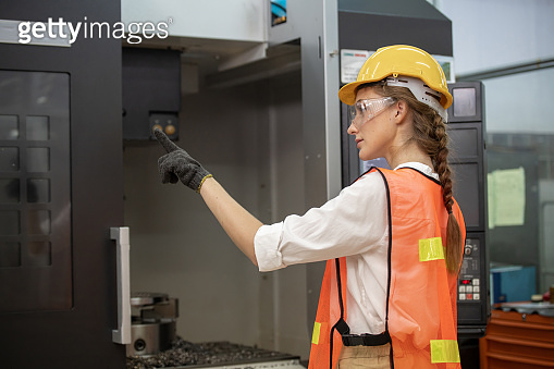 Factory worker is programming a CNC milling machine with a tablet computer. engineering and ...