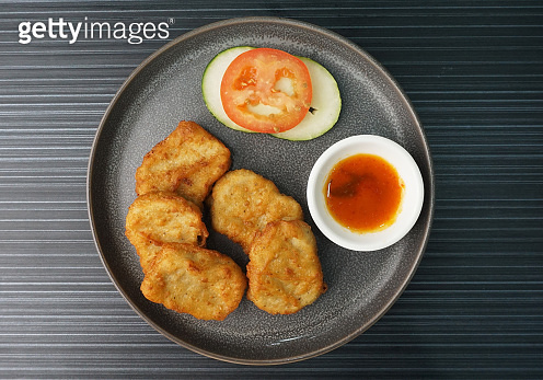 deep fried golden chicken nugget fritter with sauce on dark grey wood ...