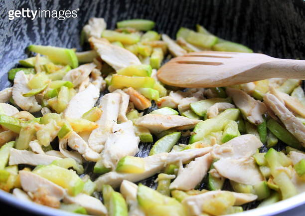 Chicken meat and fresh vegetable marrow are fried in a pan. Chicken ...