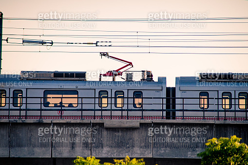 Aerial dusk shots of metro train on elevated bridge with people visible ...