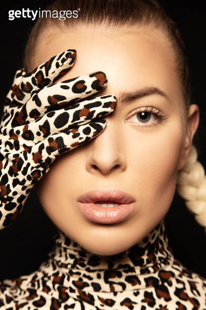 Portrait of beautiful young woman in leopard print outfit, covering one ...