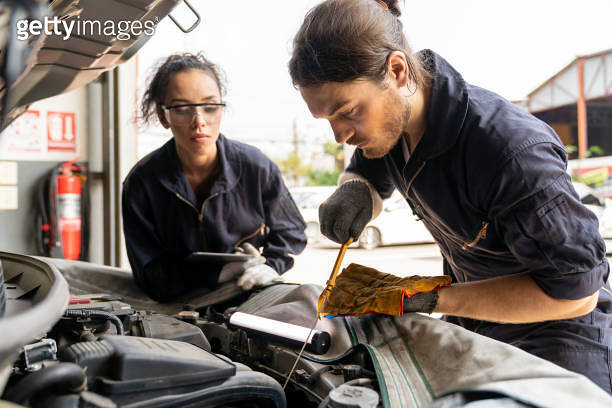 Male and female mechanic working at the garage. Group of professional ...