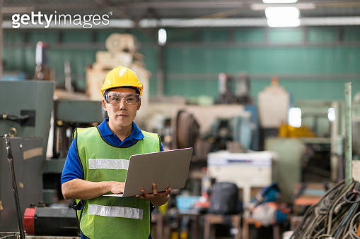 Portrait of Asian male factory worker working with laptop computer in ...