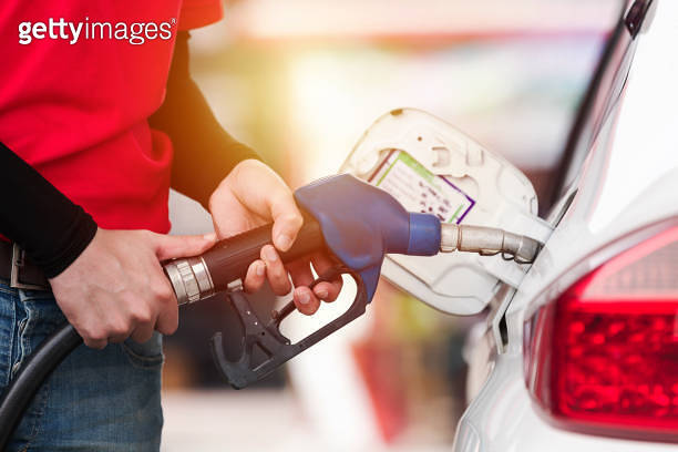 Service worker refuelling car at gas station. Hands of people ...