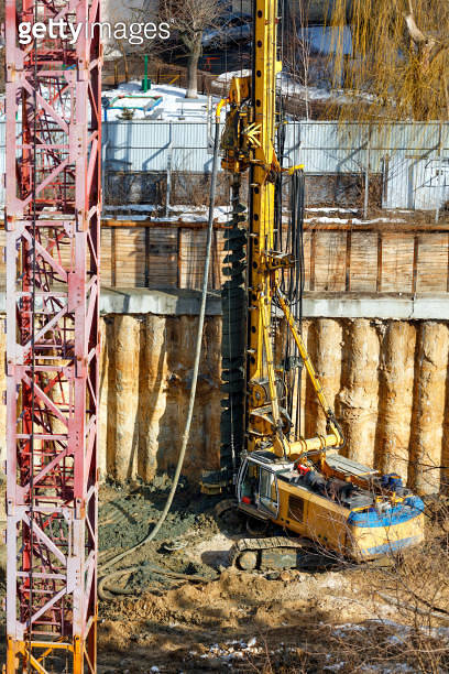 A heavy excavator, together with a drilling rig, is working at a ...