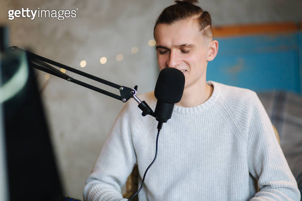 Young man makes a podcast audio recording at home. Man using pc and two ...