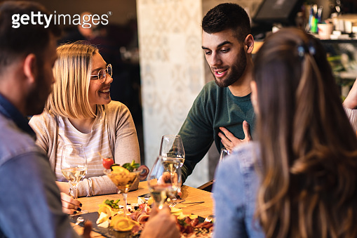 Group of young friends having fun in restaurant, talking and laughing ...