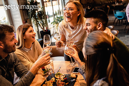 Group of young friends having fun in restaurant, talking and laughing ...